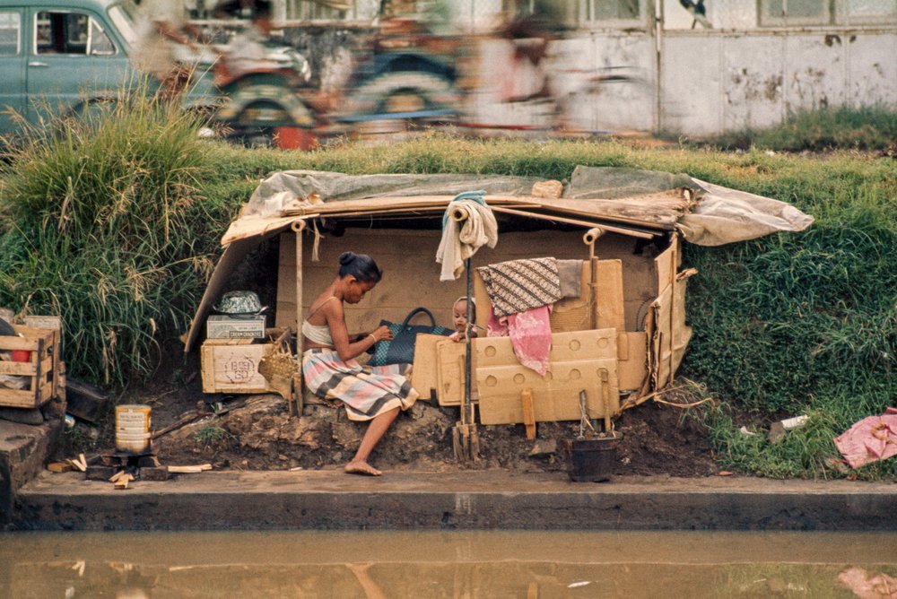 Cardboard hut, along a sewage canal, serves as a home. Jakarta, Indonesia