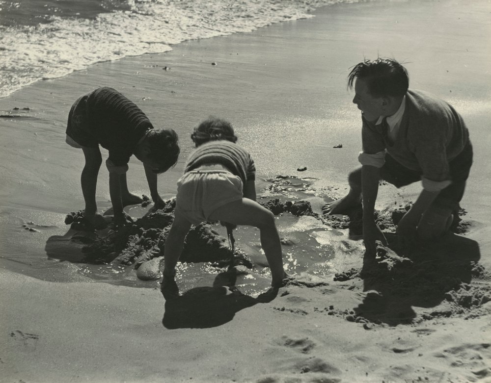 Three kids playing with sand at the beach