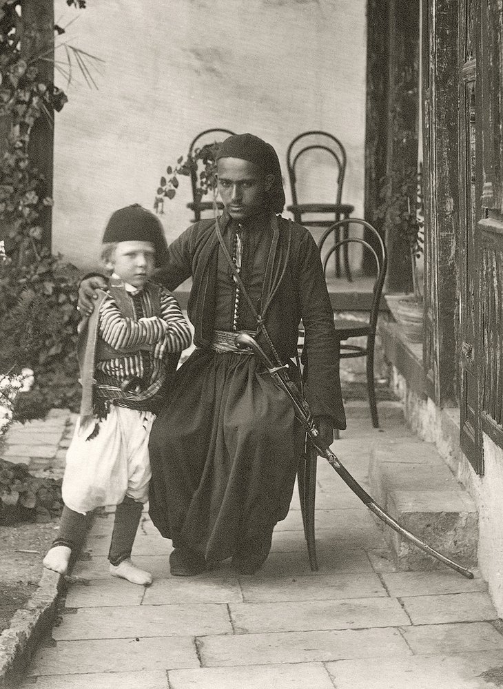 Arab kawass (Ottoman guard) with a young boy in the garden of a house ...
