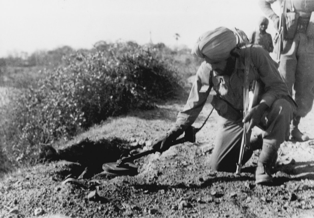 An Indian soldier searching for mines with a metal detector