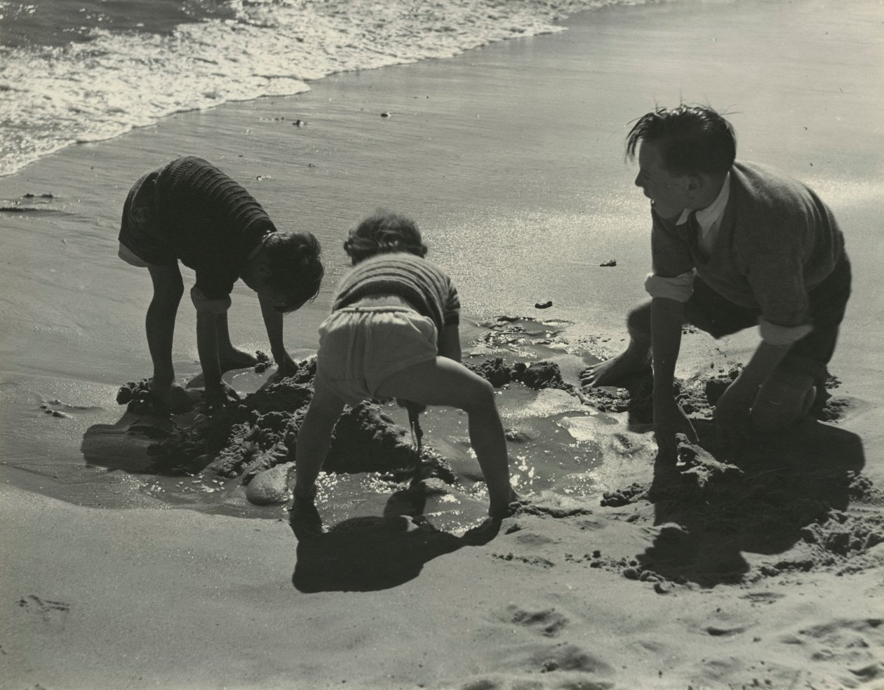 Three kids playing with sand at the beach