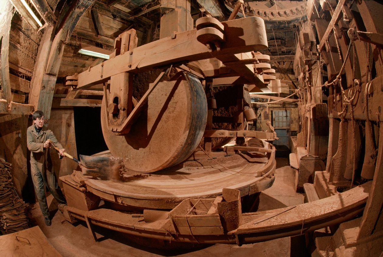 A man grinds cacao bean shells for animal feed in a 100-year-old mill ...