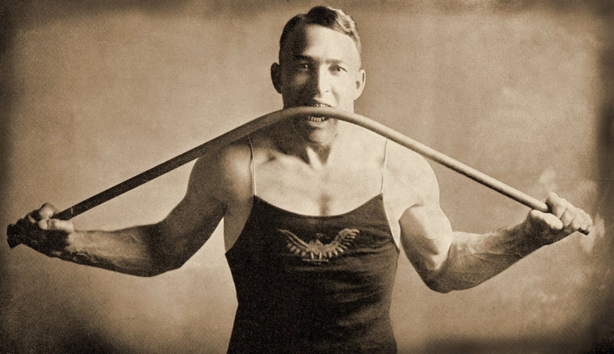 Californian Strongman Mr. P. A. Linebarger bends an iron bar with his ...